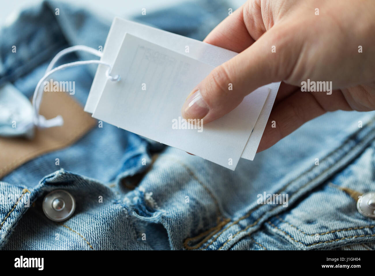 close up of hand holding price tag of denim jacket Stock Photo - Alamy
