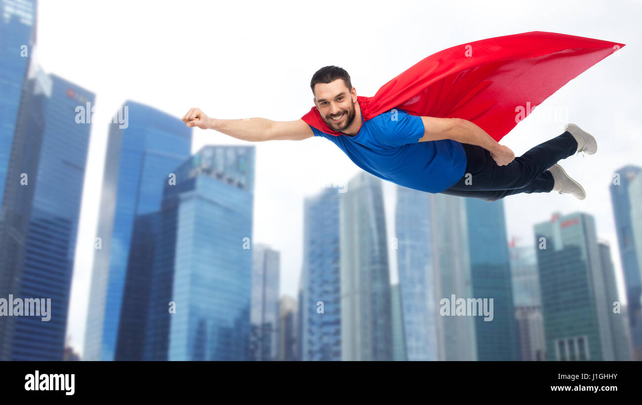 happy man in red superhero cape flying over city Stock Photo - Alamy