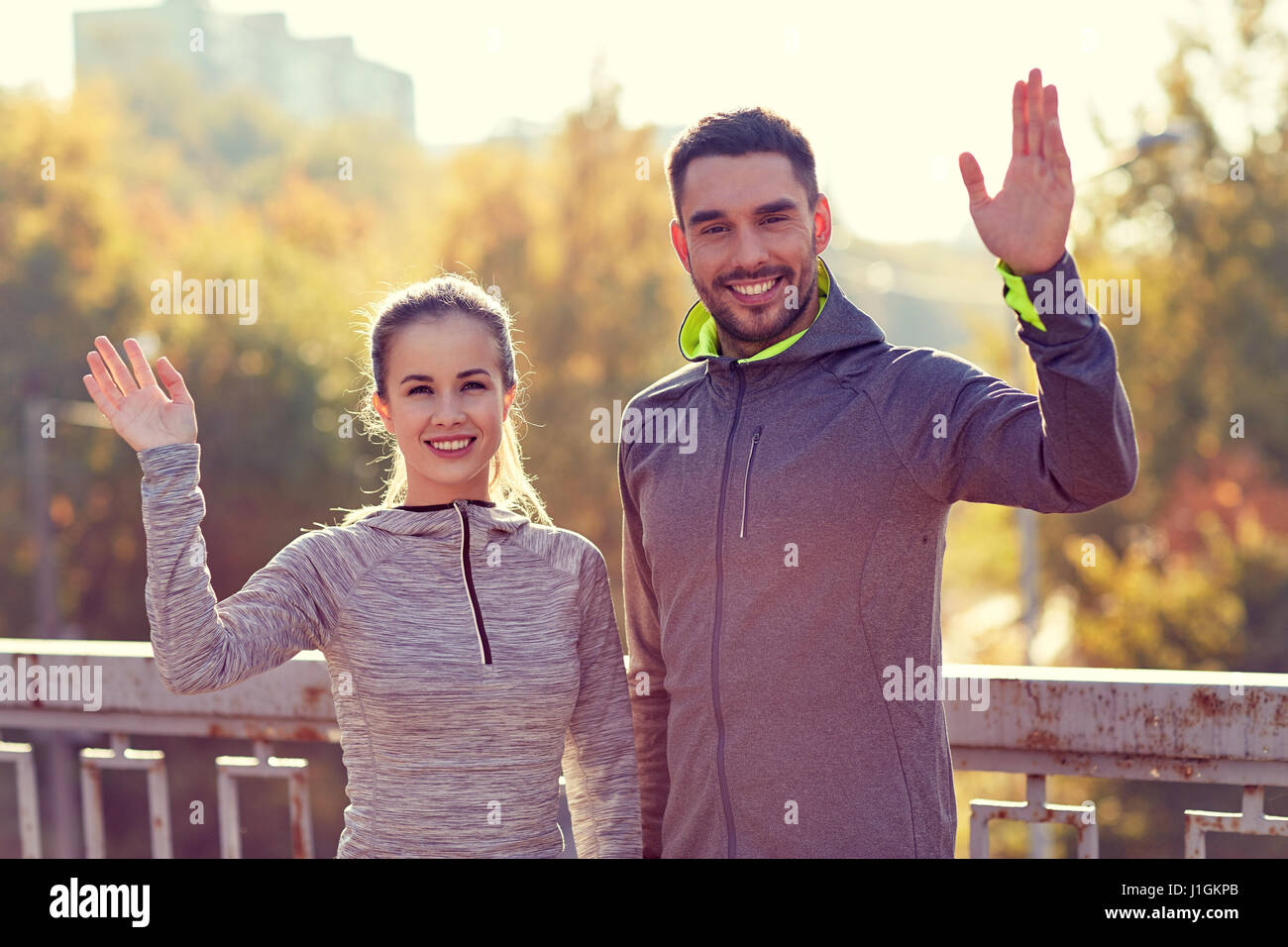 smiling couple waving hand outdoors Stock Photo - Alamy