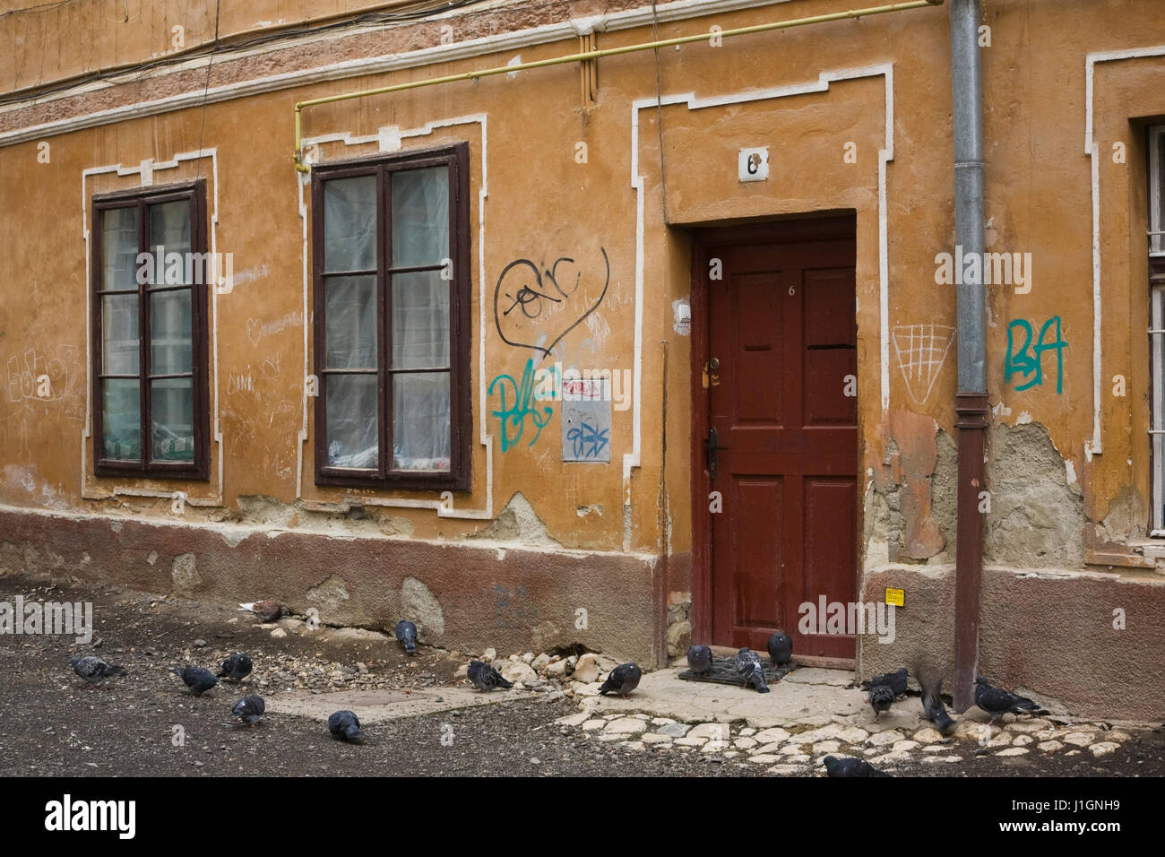 Old residential building facade with crumbling concrete and graffiti on ...