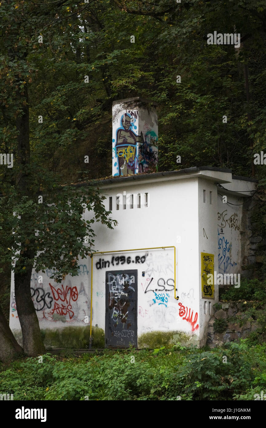 Small white utility building covered with graffiti in a park, Brasov ...