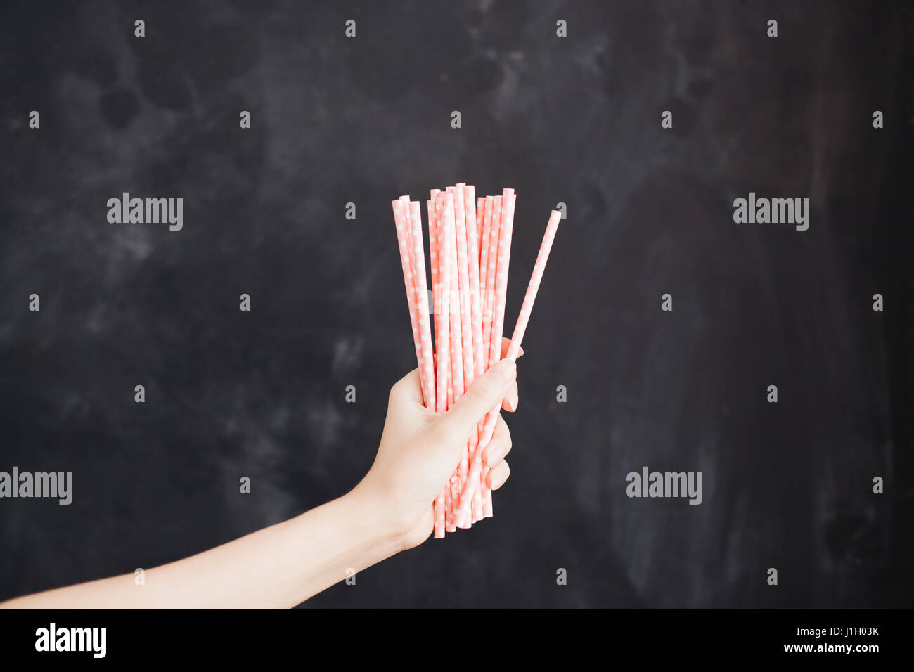 Woman hand hold cocktail straw on black background Stock Photo - Alamy