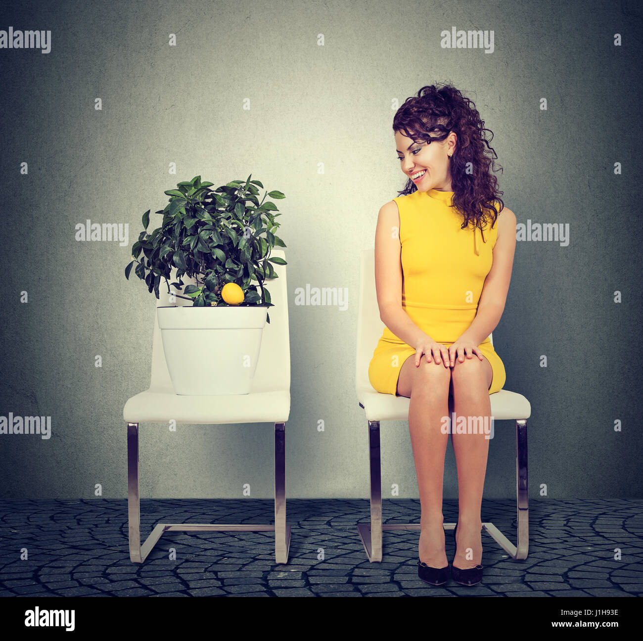 beautiful woman sitting on chair looking at lemon tree, smiling Stock ...