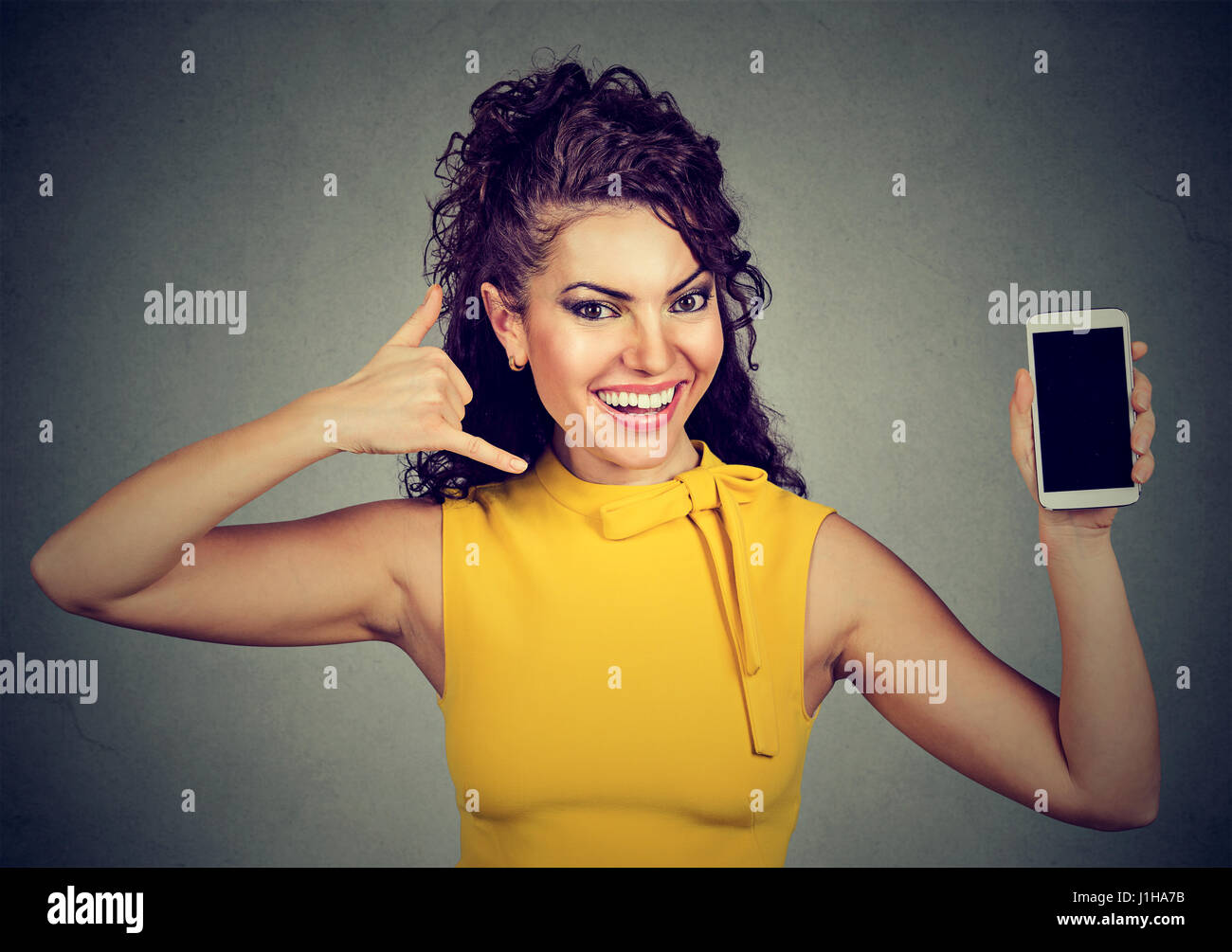 Young pretty woman holding mobile phone showing call me sign hand ...