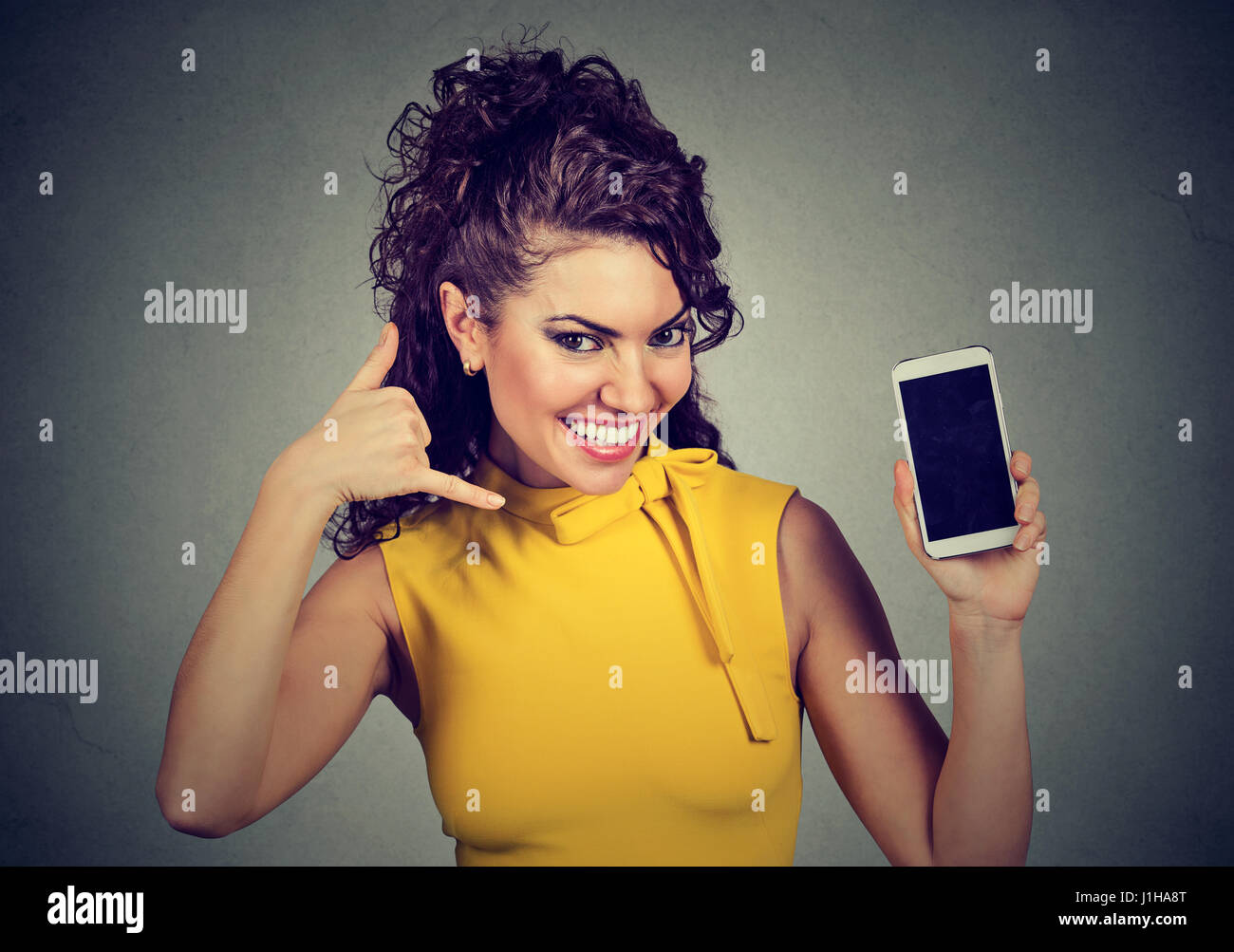 Pretty woman holding mobile phone showing call me hand gesture looking ...
