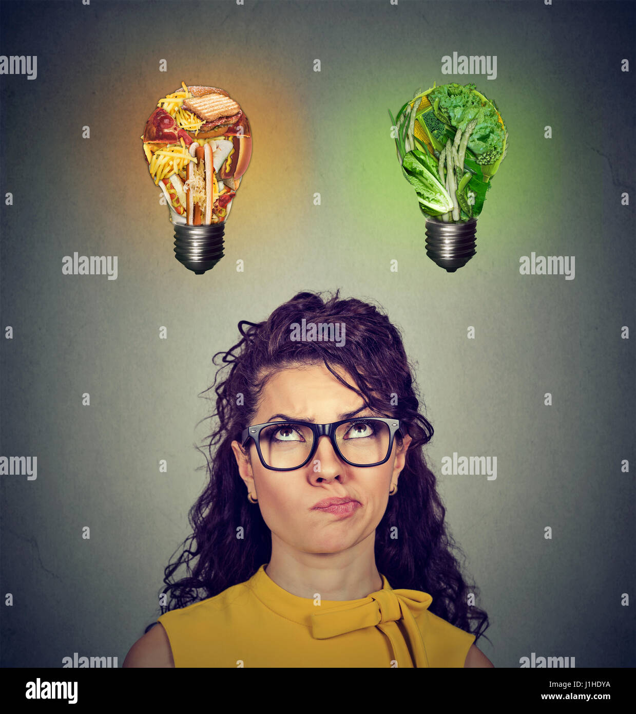 Woman thinking looking up at junk food and green vegetables light bulb ...