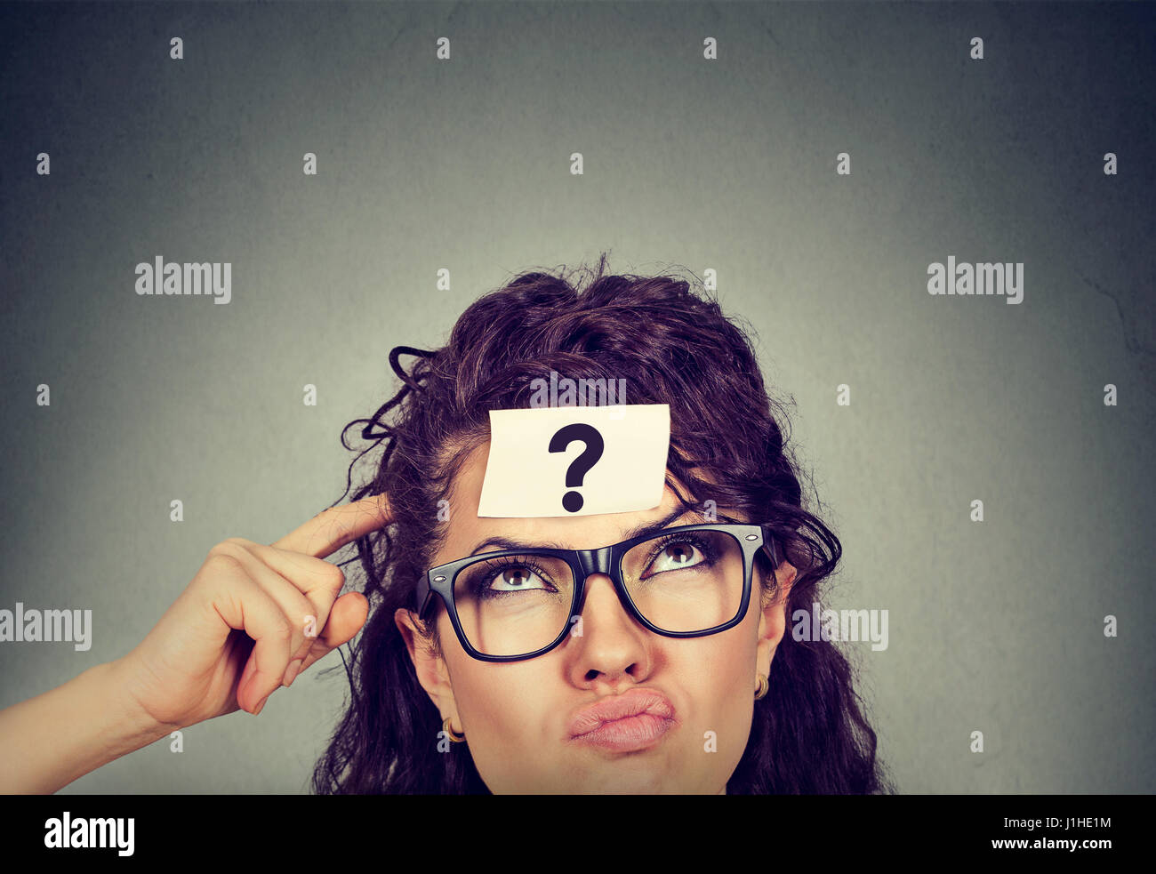 Thinking perplexed woman with question mark isolated on gray wall ...