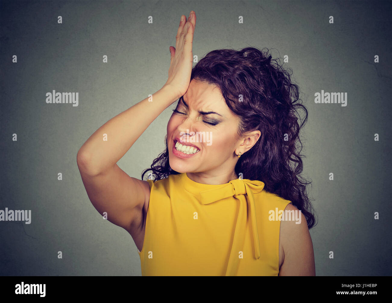 Regrets wrong doing. Silly young woman, slapping hand on head having ...