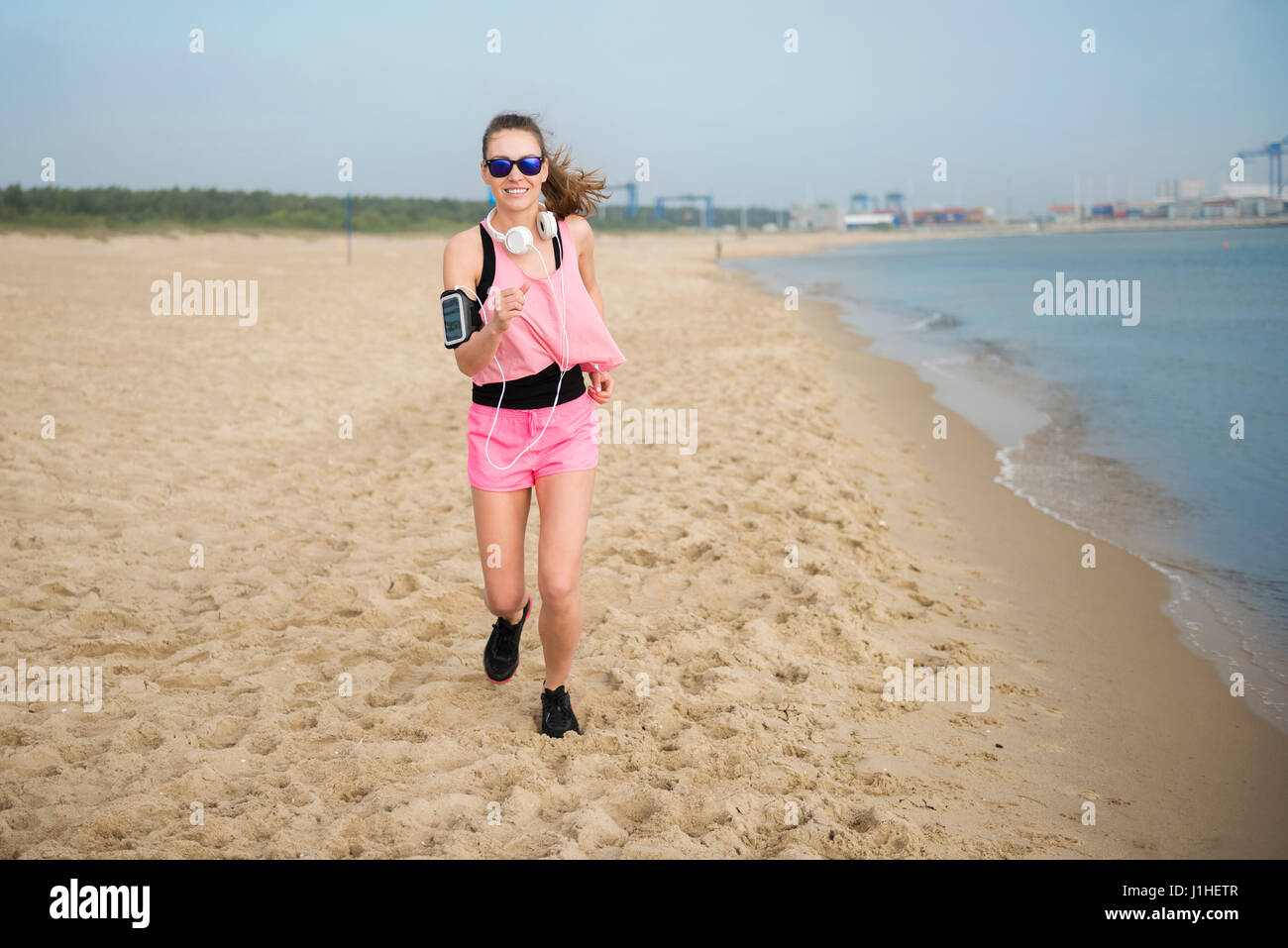 Young woman running across the beach Stock Photo - Alamy