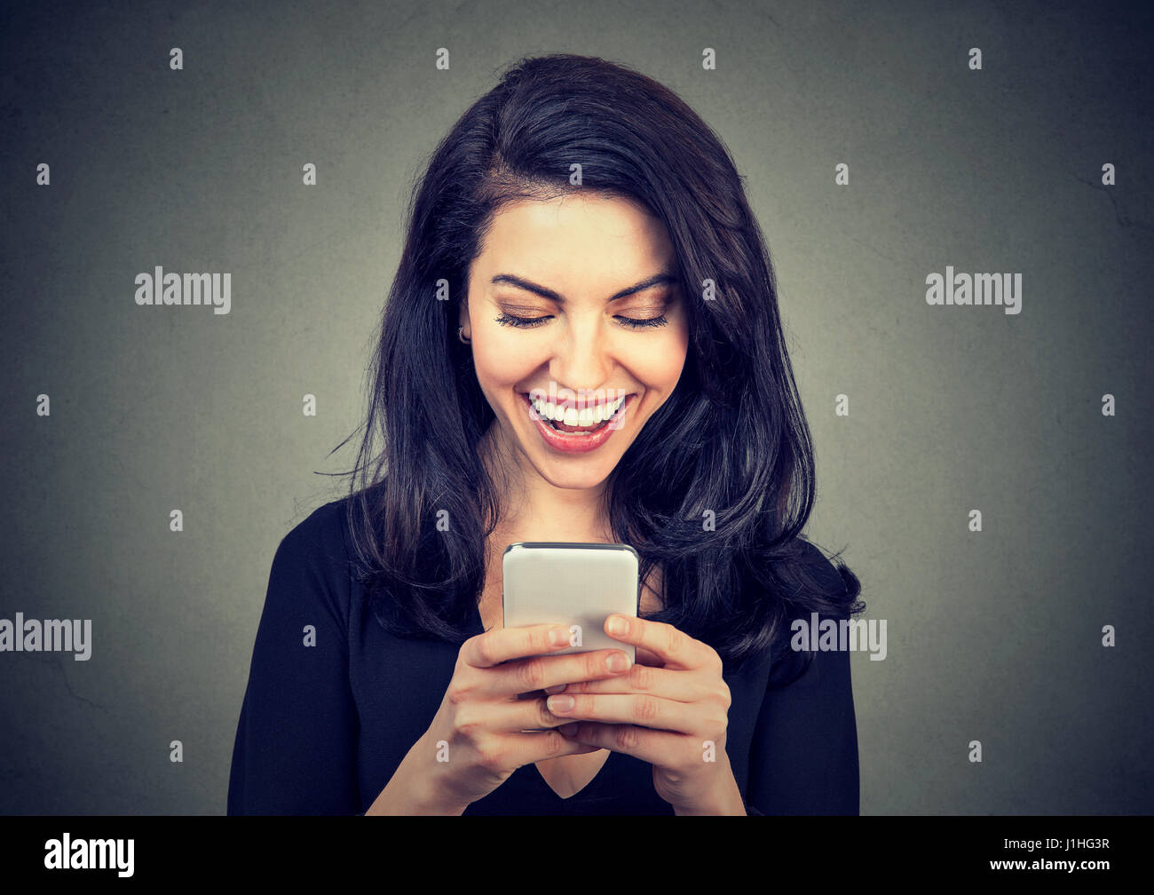 Laughing young woman text messaging on smart phone having a pleasant chart conversation isolated ...