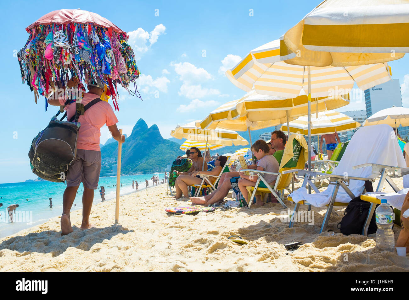 RIO DE JANEIRO - JANUARY 24, 2017: Beach vendors pass beachgoers ...
