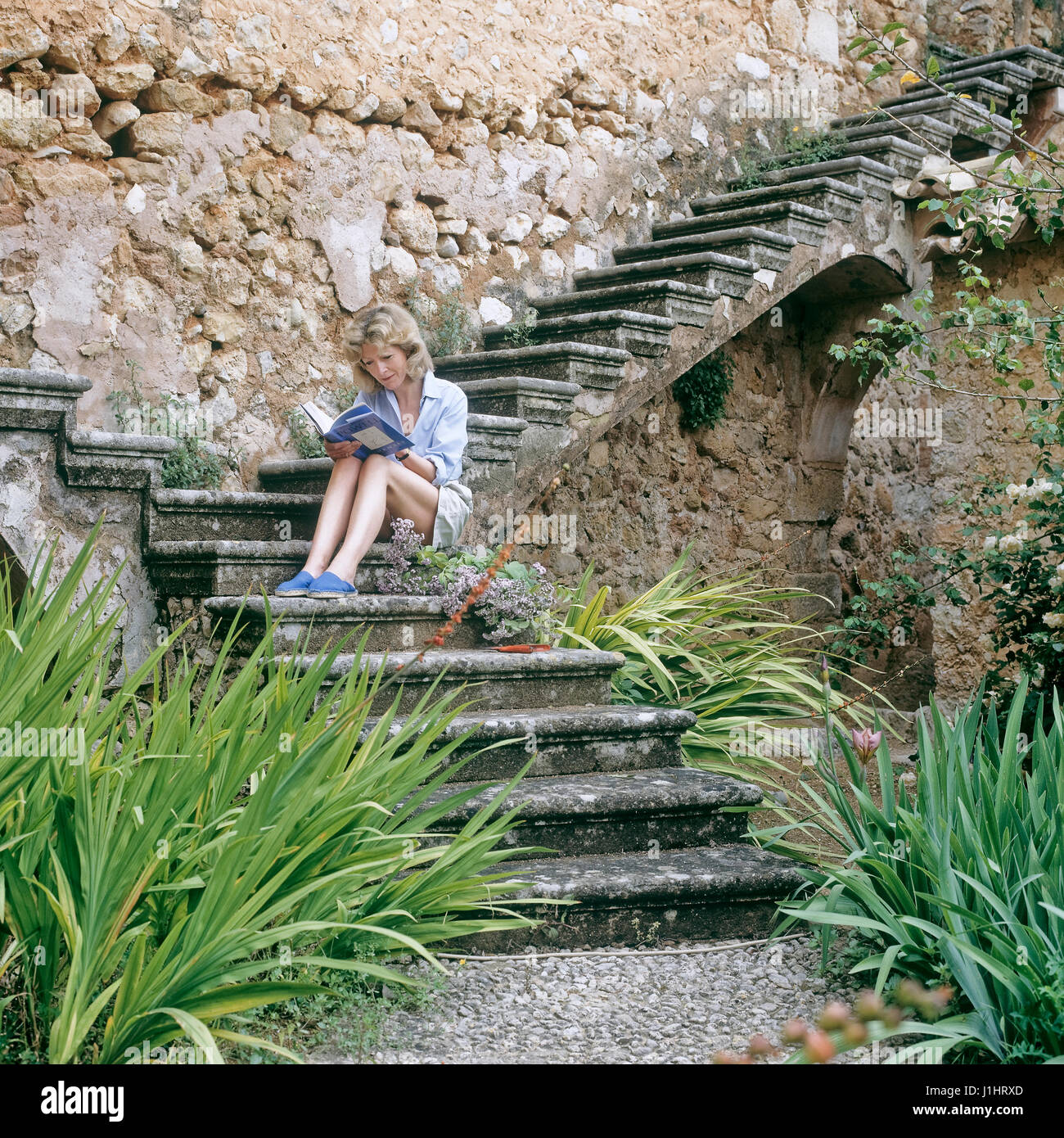 Woman reading book on staircase Stock Photo - Alamy