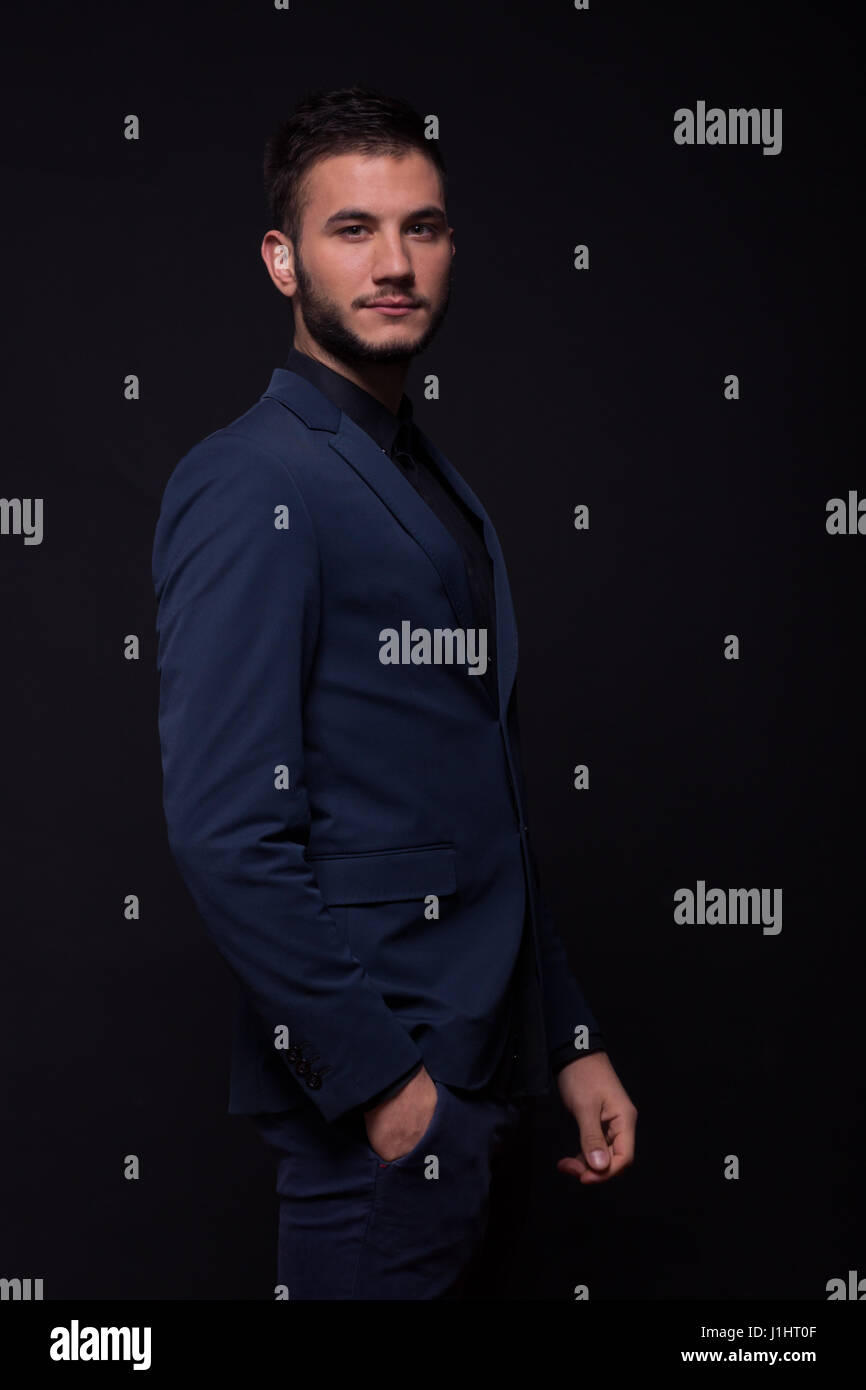 young adult man, profile, elegant suit blue jacket, black background ...