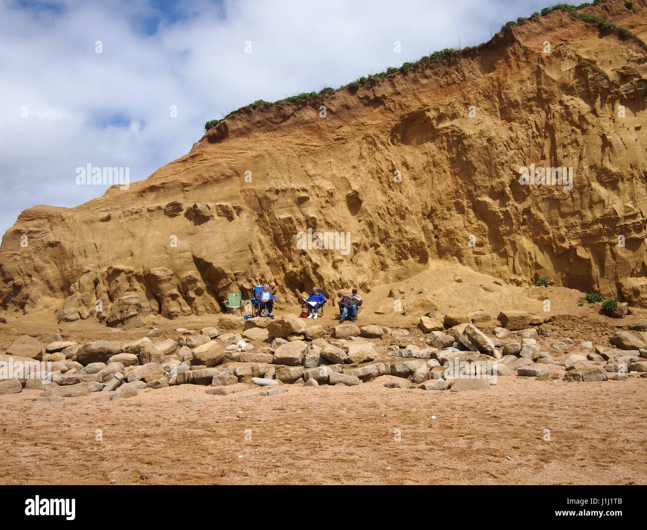people sitting under dangerous cliff Stock Photo - Alamy