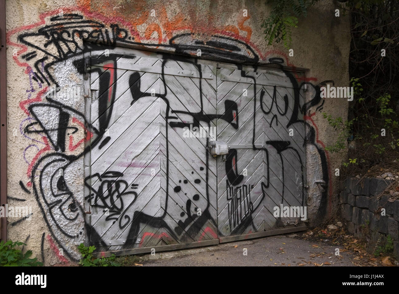 Trash and graffiti on the garage doors at the back of a building ...