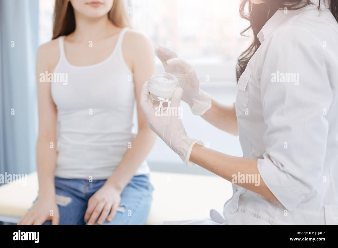 Female dermatologist applying medical cream on patient in the hospital ...