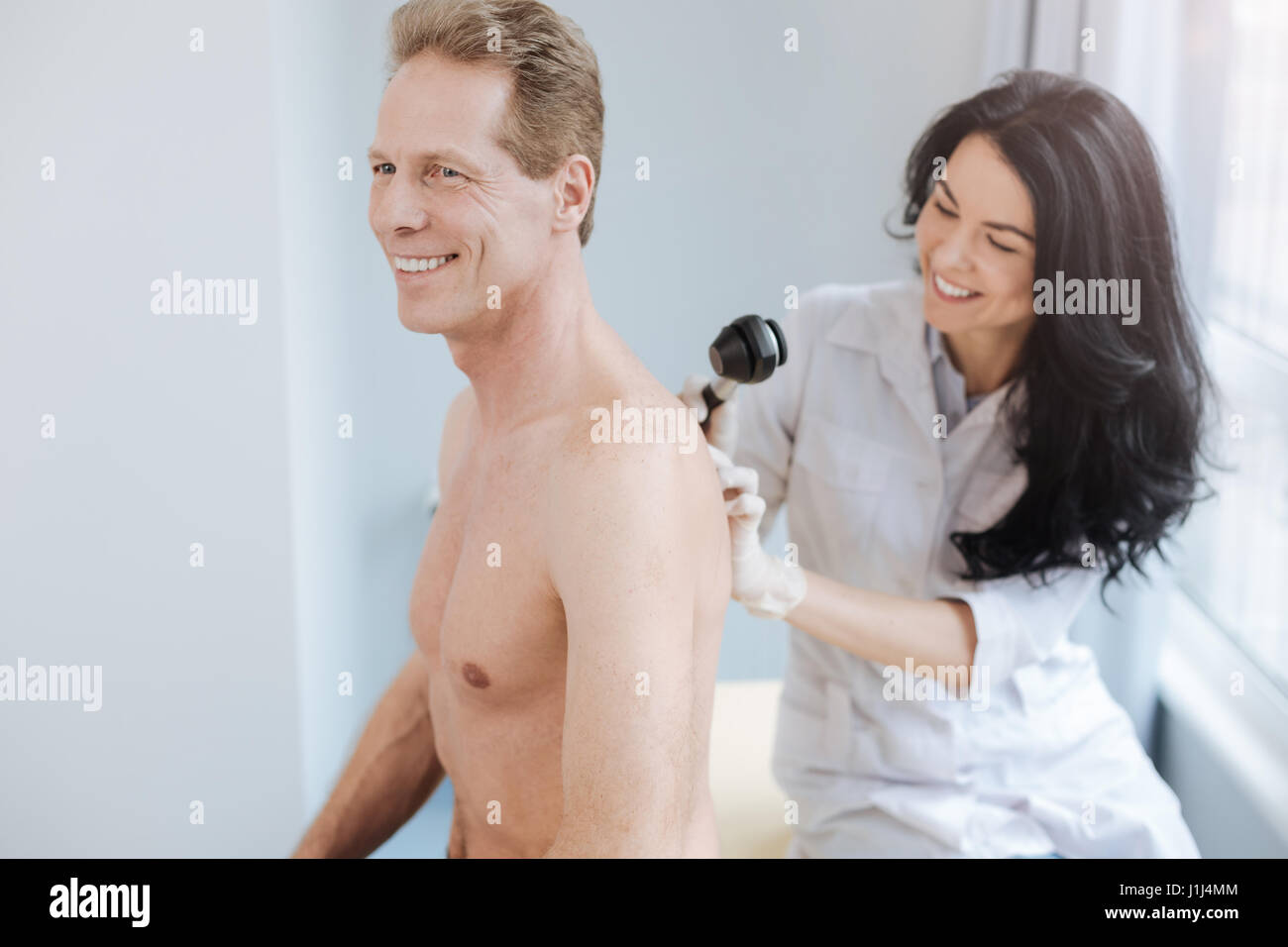 Smiling doctor using dermatoscope for skin problem examination in the ...