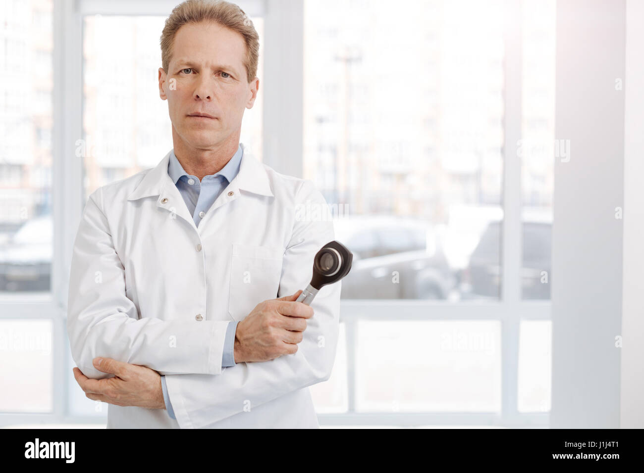 Confident aged dermatologist holding dermatoscope at work Stock Photo ...