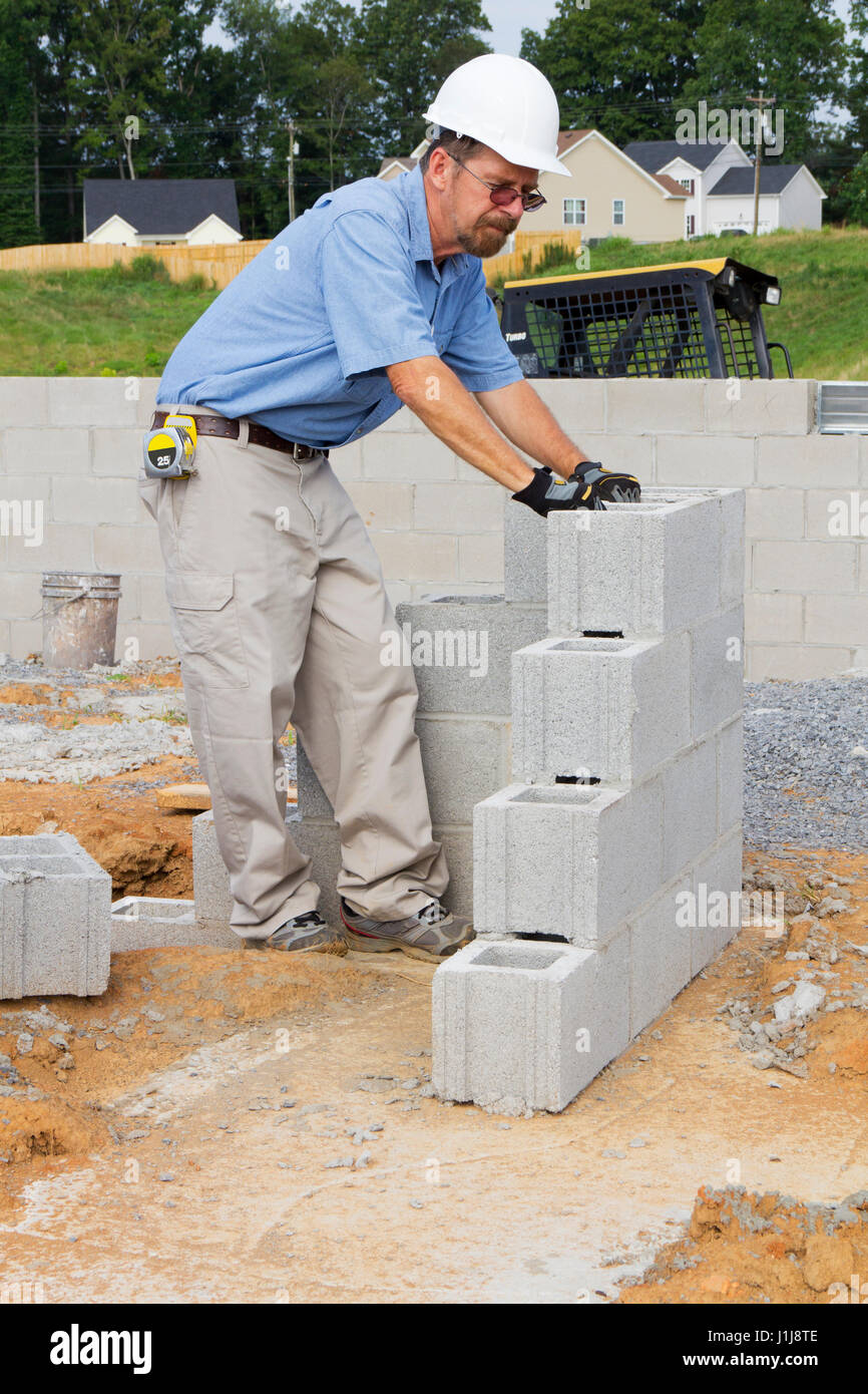 Supervisor checking cinder block where masons strated building walls ...