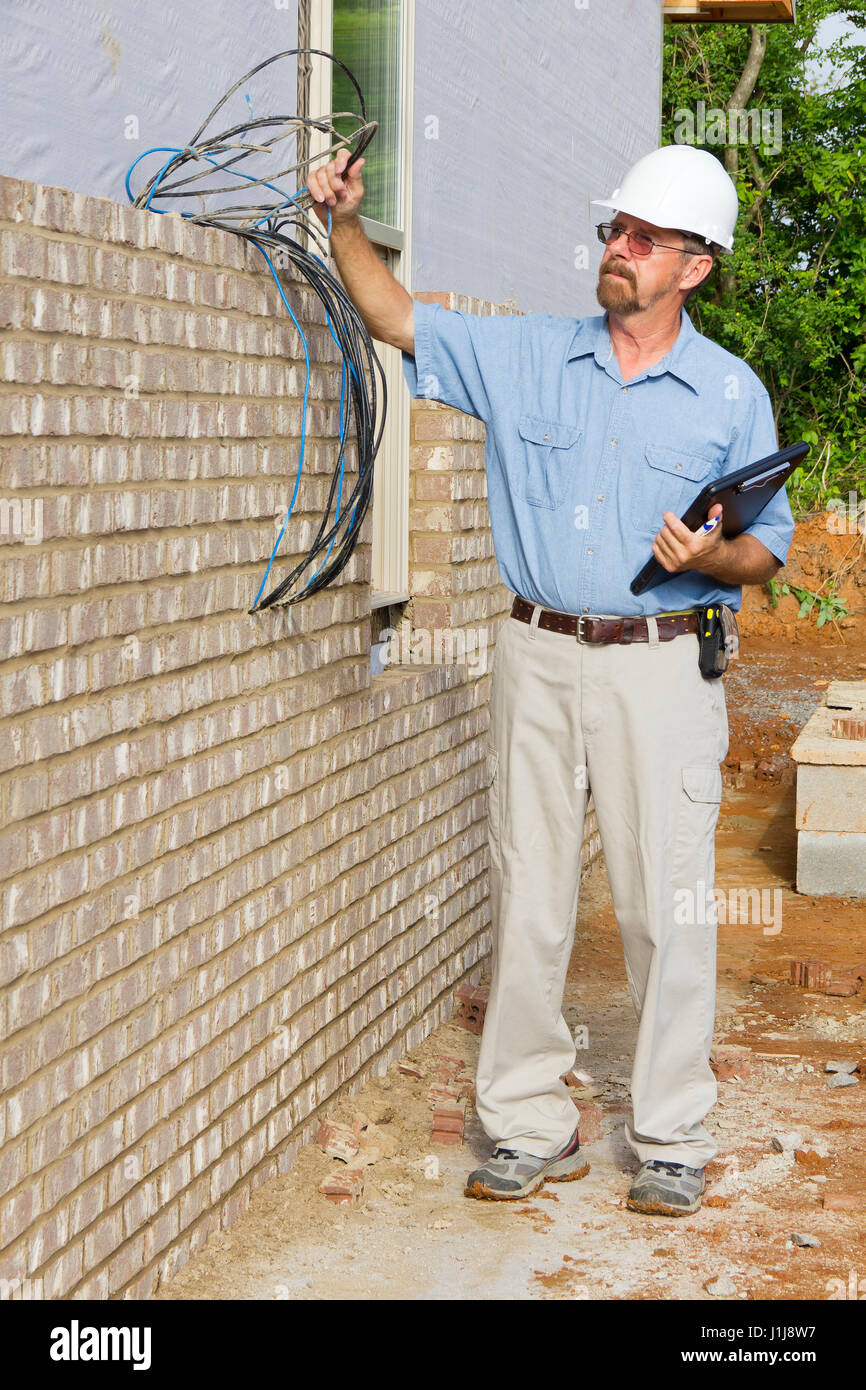 Building inspector checking electrical wires,phone lines, building ...