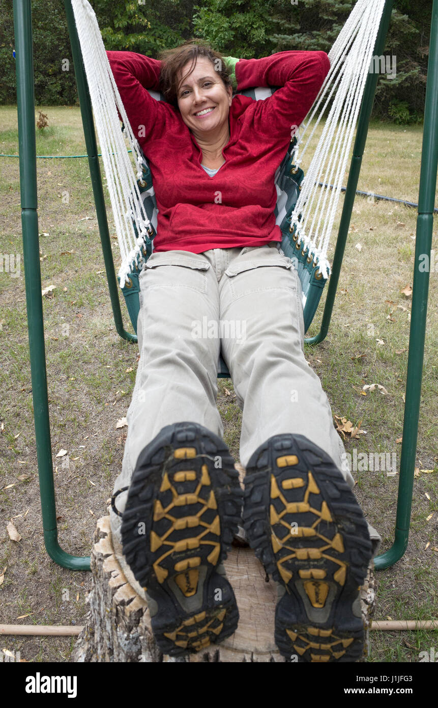 Woman relaxing in a swing chair with log foot stool. Clitherall ...