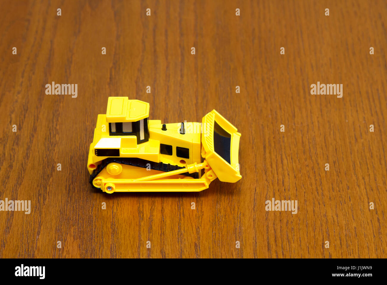 Bulldozer toys with wheels made of plastic isolated on a wood grain ...