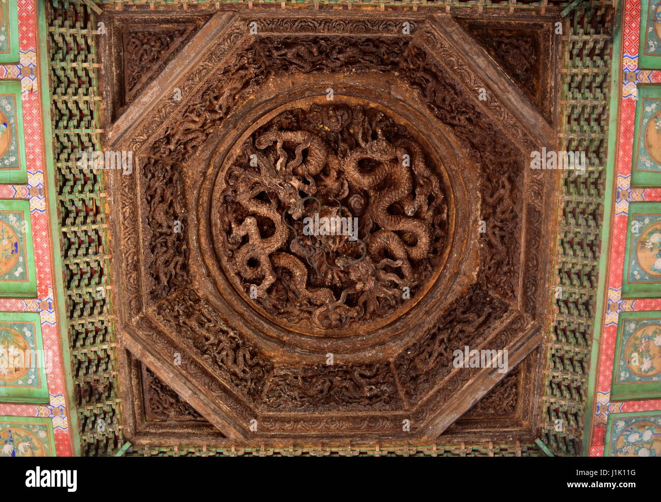 Wood carved Chinese dragons decorating the ceiling of a gazebo in the ...