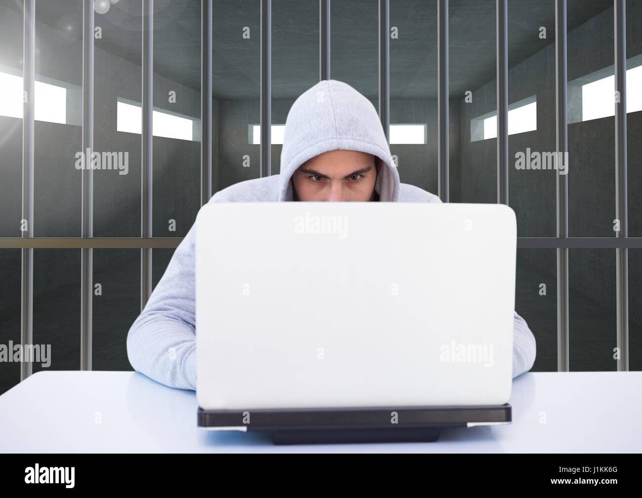 Digital composite of Criminal in hood with laptop behind prison bars ...
