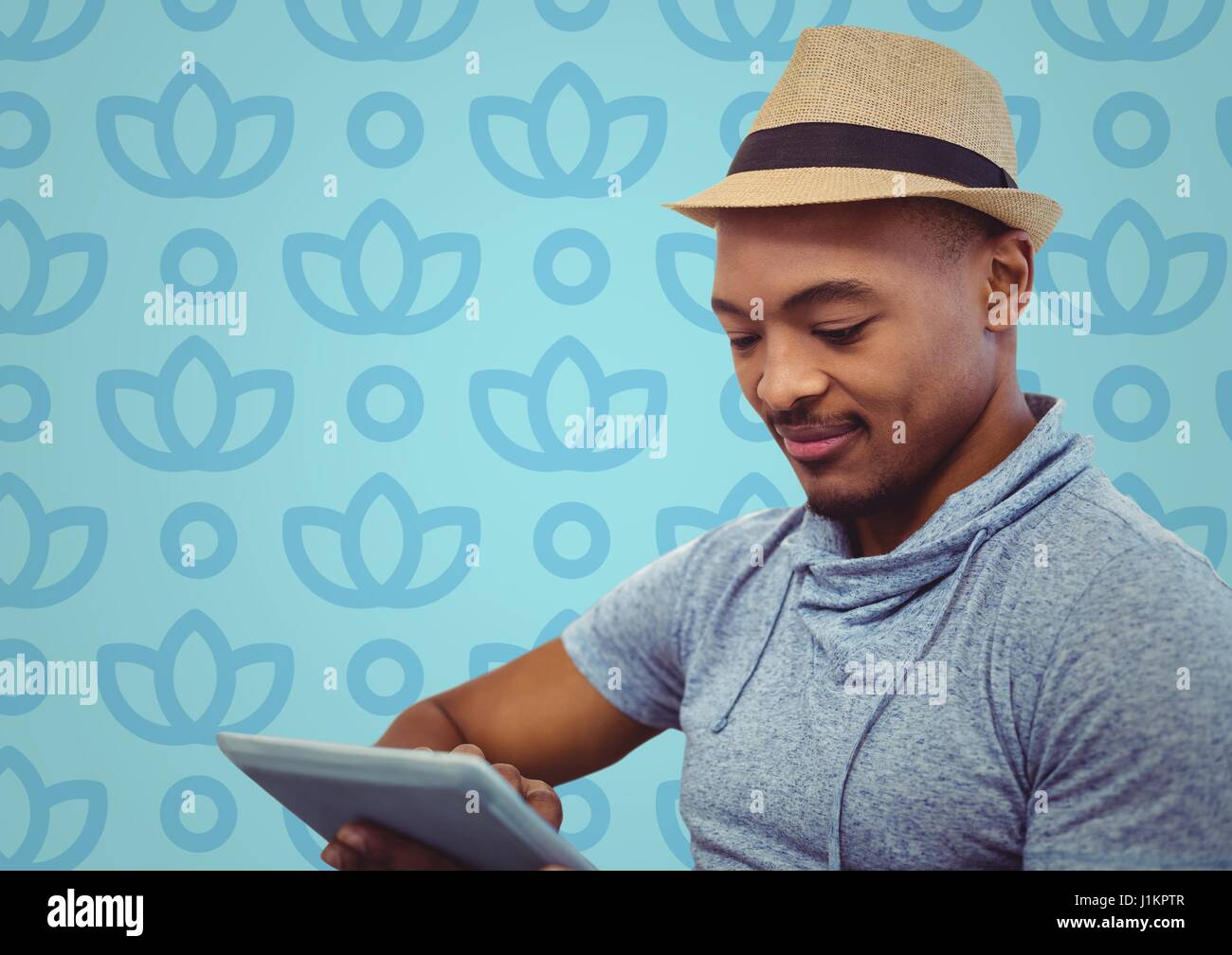 Digital composite of Man in fedora with tablet against blue floral ...