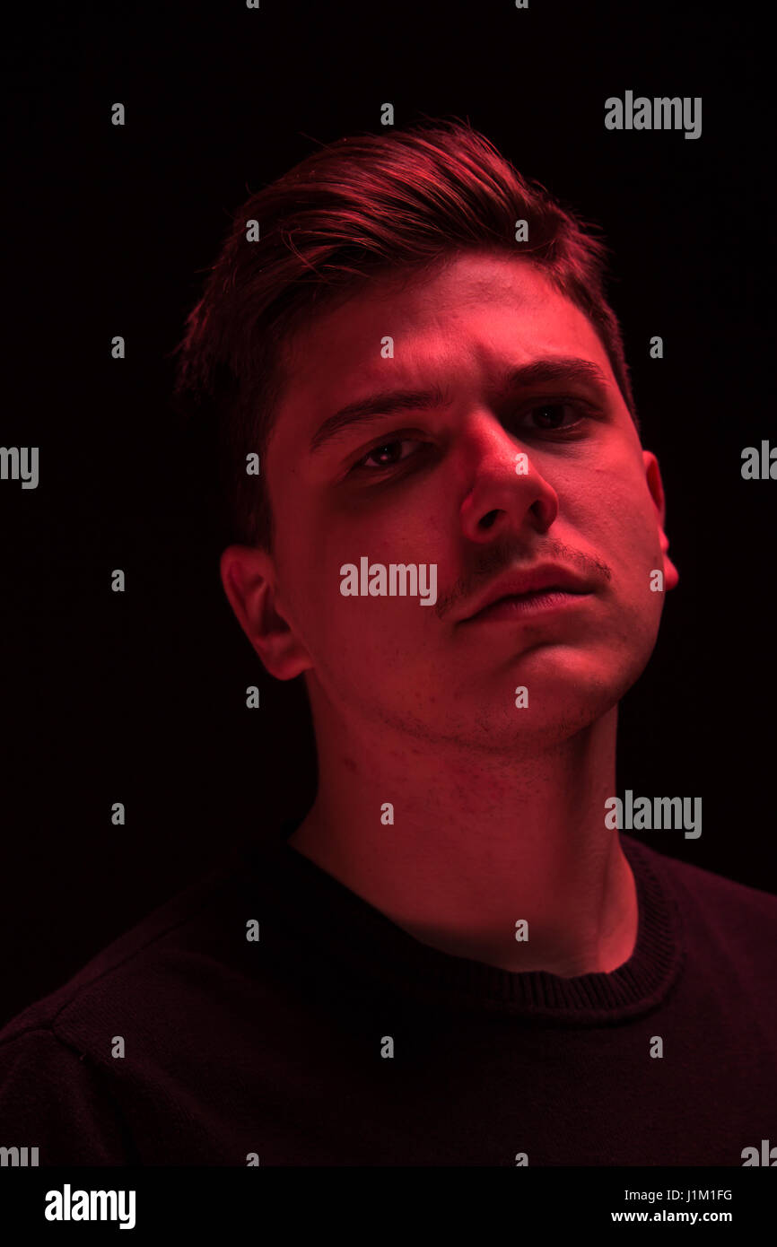 one young adult man, looking above, looking up, red color light, black ...