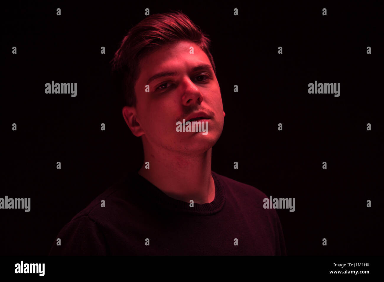 one young adult man, looking above, looking up, red color light, black ...
