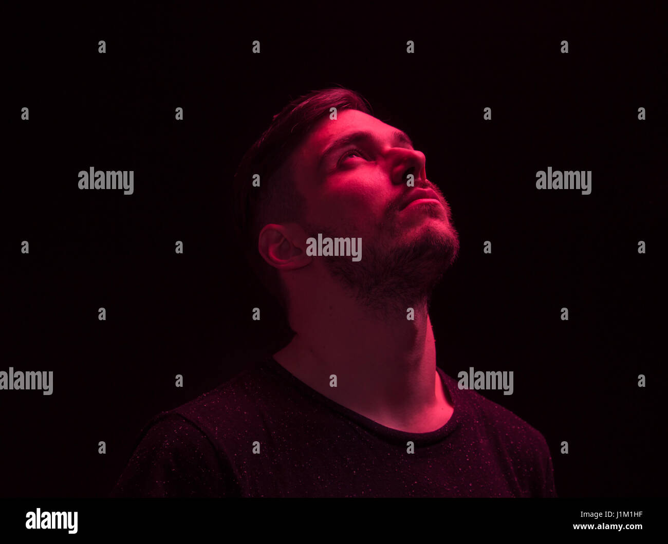 one young adult man, looking above, looking up, red color light, black ...