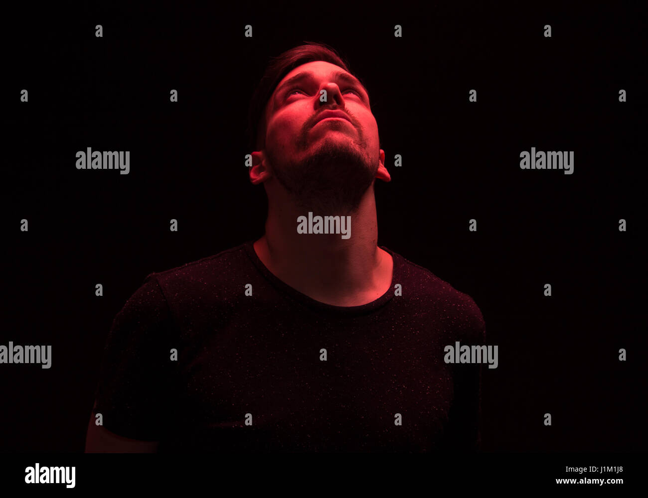 one young adult man, looking above, looking up, red color light, black ...
