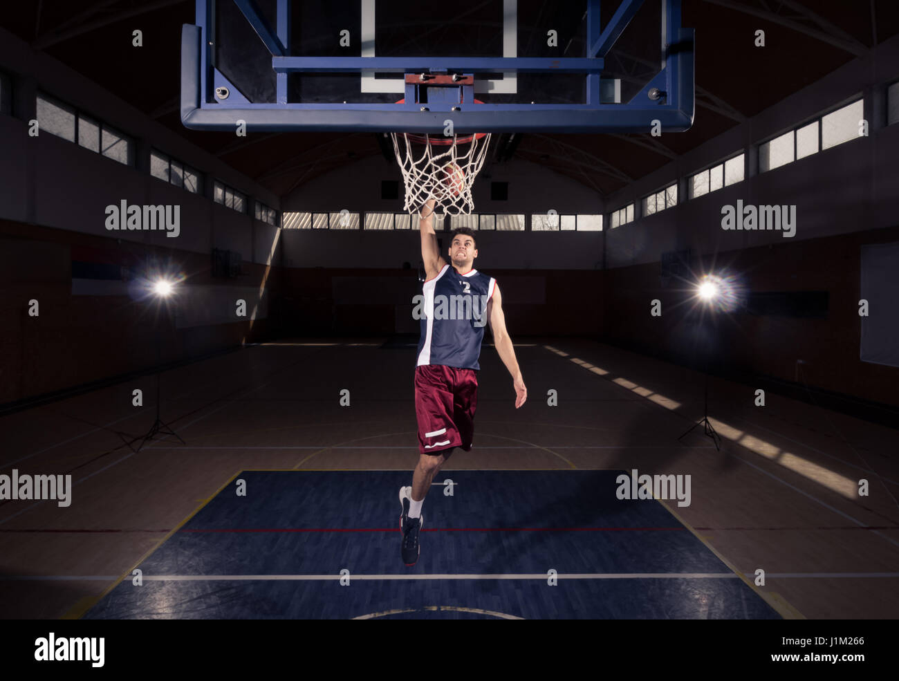 one young adult man, basketball player dunk in air, slam dunk, indoors ...