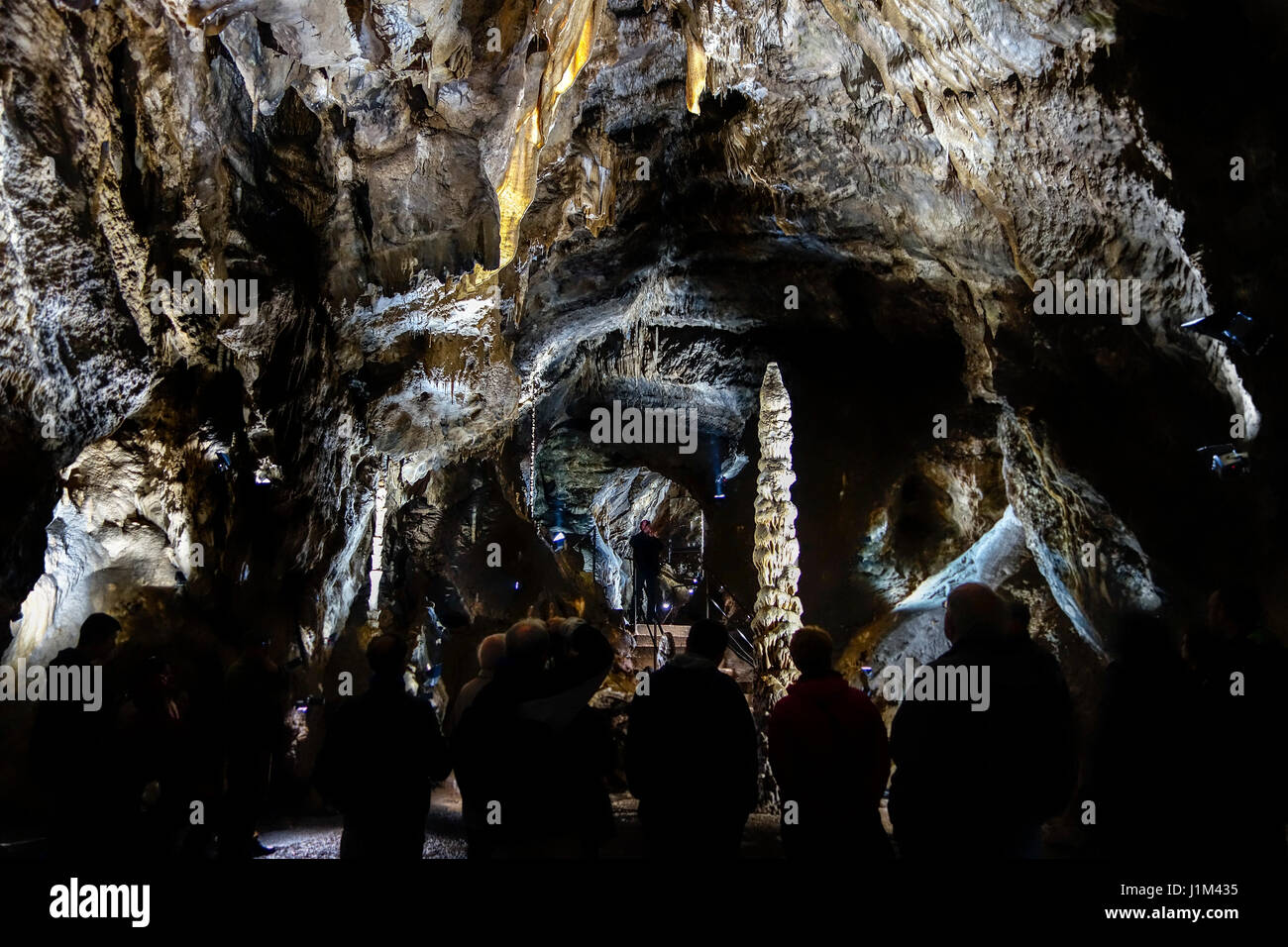 Tourists looking at big stalagmite during guided tour in the Caves of ...