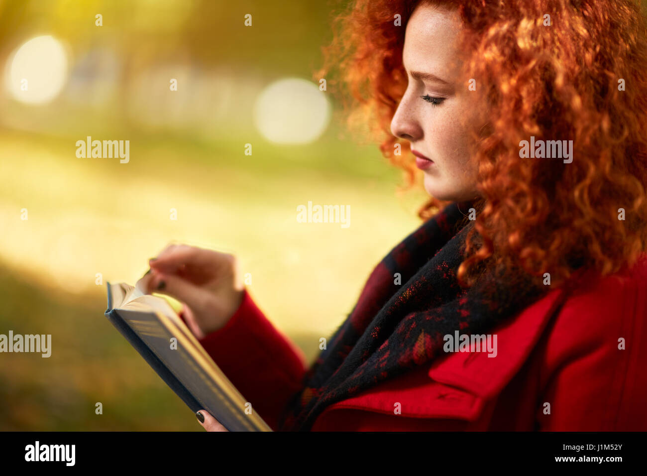 Profile of ginger female reading book outside Stock Photo - Alamy