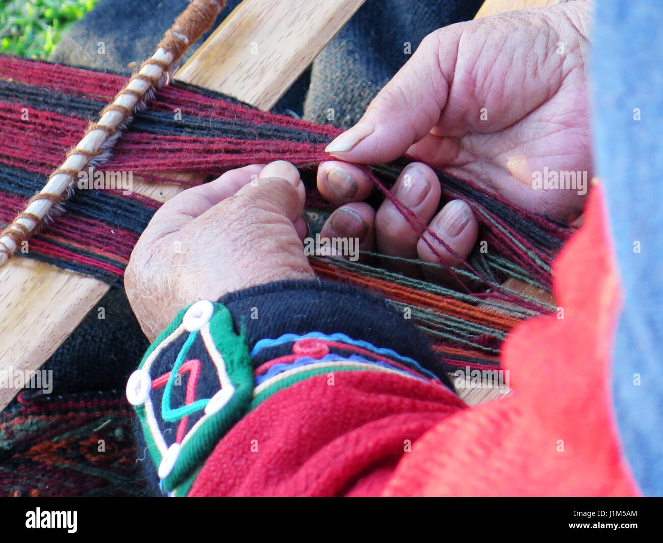 Close up of Peruvian lady in authentic dress spinning yarn by hand ...