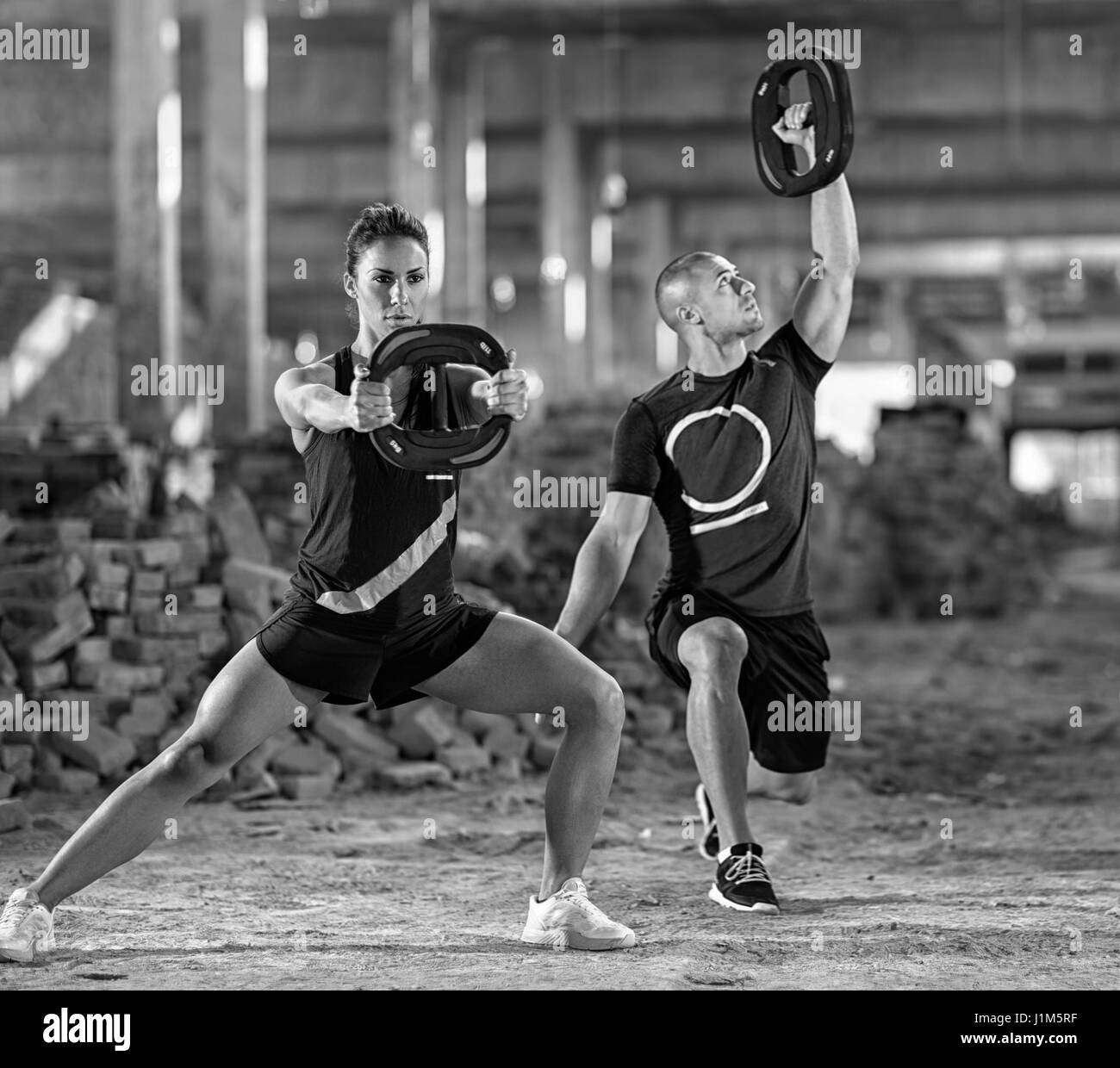 Group of young sporty people exercise with weights in unfinished ...