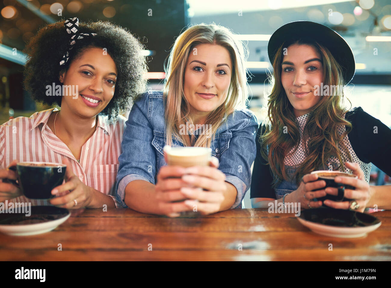 Three attractive multiracial young female students sitting close ...