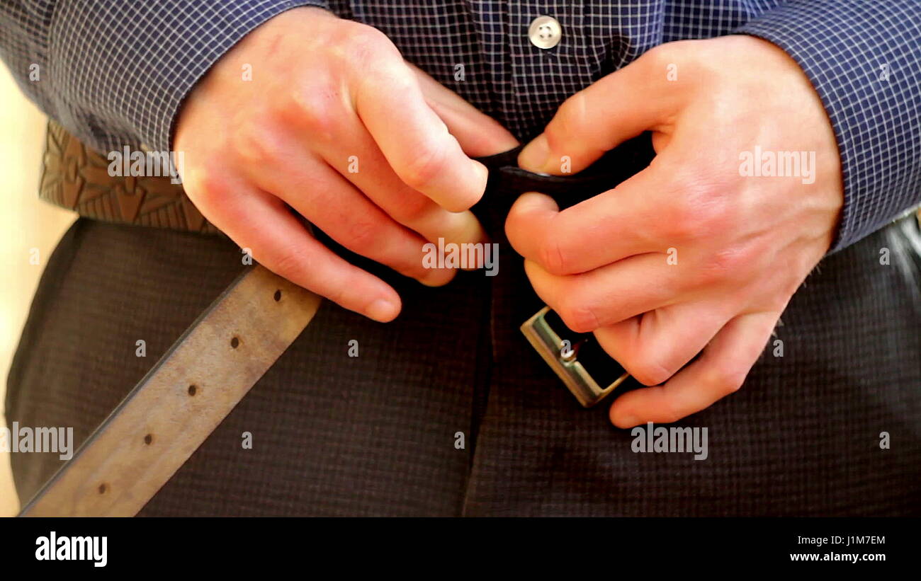 Man in blue shirt buckling undoes the belt on his pants Stock Photo - Alamy