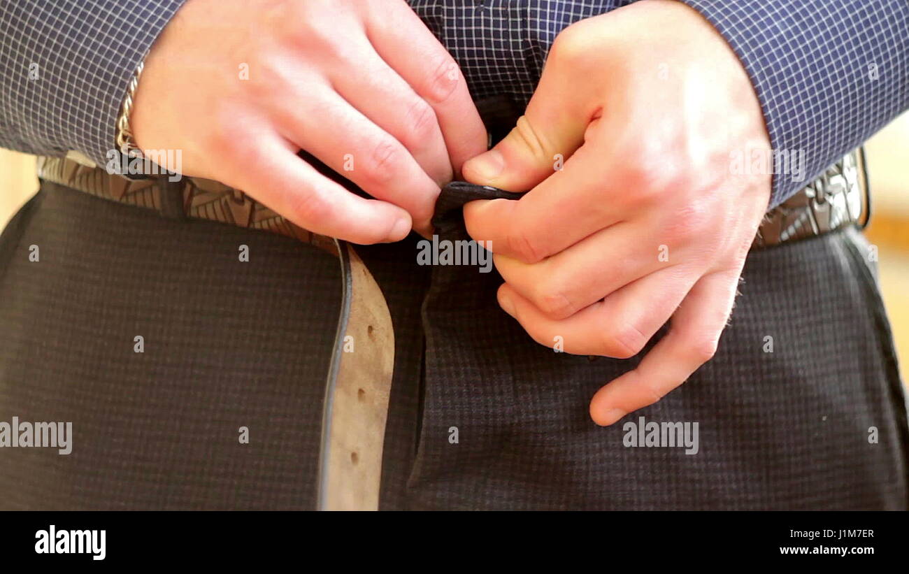 Man in blue shirt buckling undoes the belt on his pants Stock Photo - Alamy