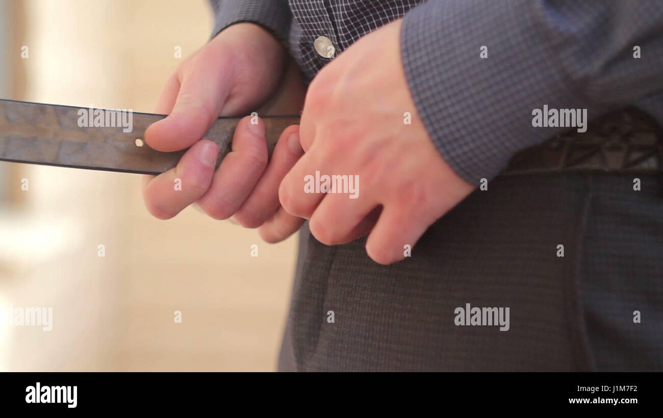 Man in blue shirt buckling undoes the belt on his pants Stock Photo - Alamy