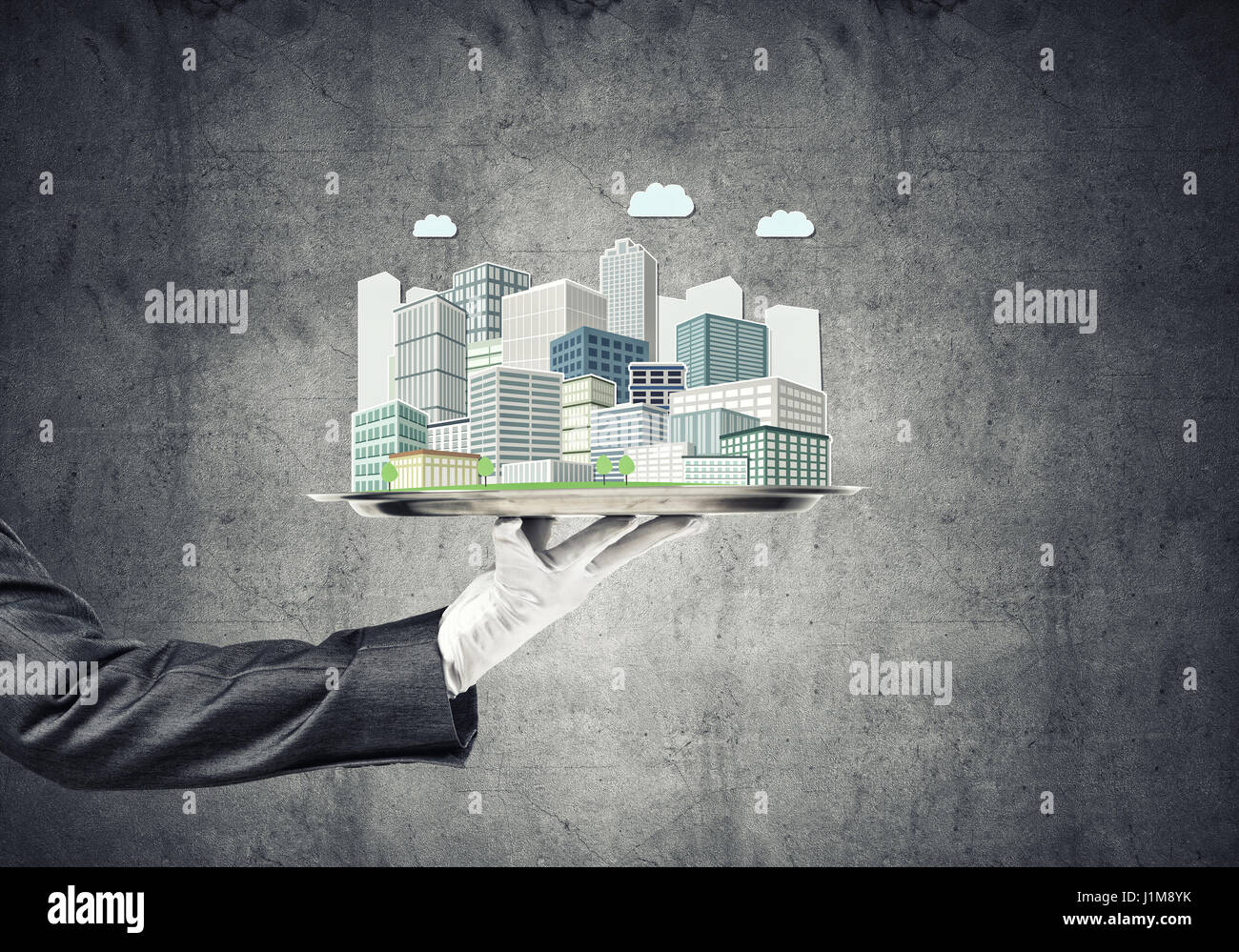 Hand holding metal tray with modern city model against concrete ...