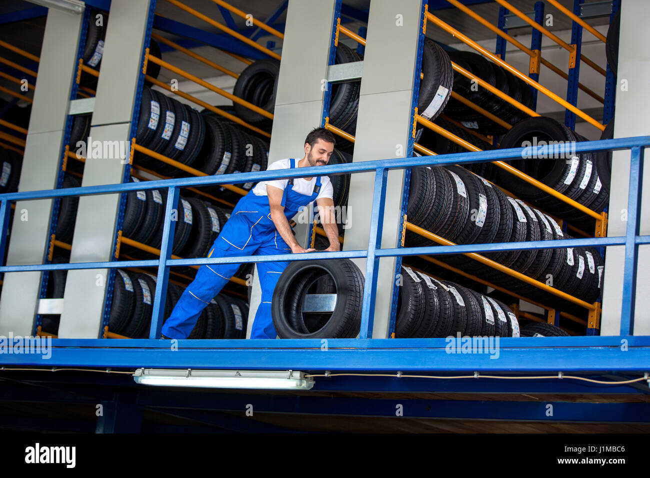auto mechanic pushes the tire in tire store Stock Photo - Alamy