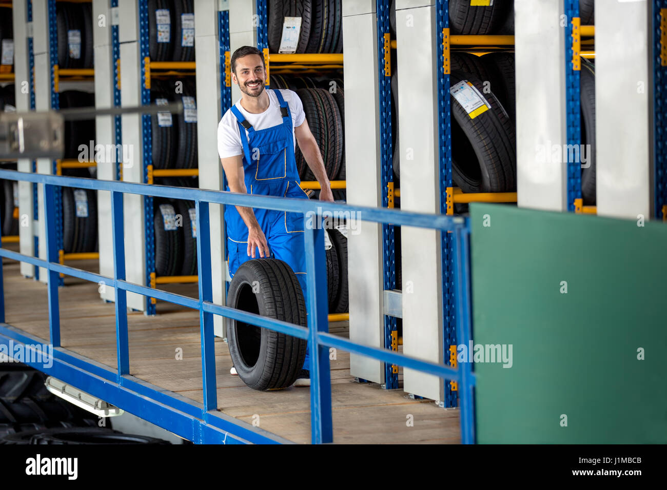 Smiling mechanic pushes the tire in tire store Stock Photo - Alamy