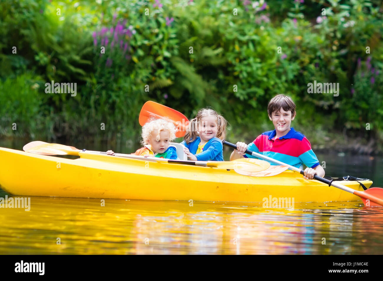 Happy family with three kids enjoying kayak ride on beautiful river ...