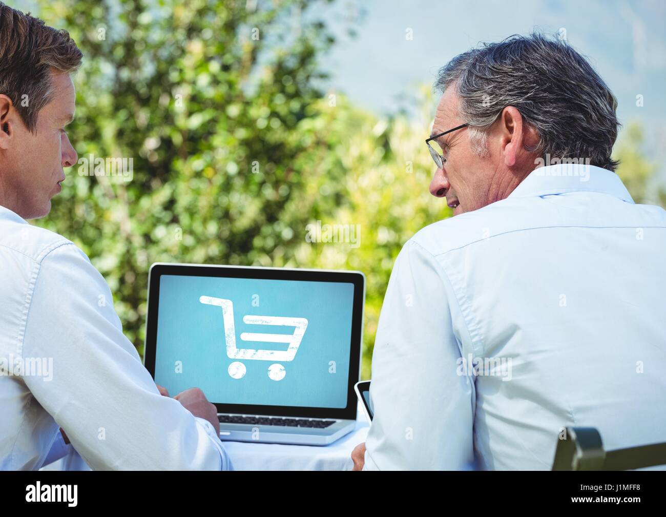 Digital composite of Two men using Laptop with Shopping trolley icon ...