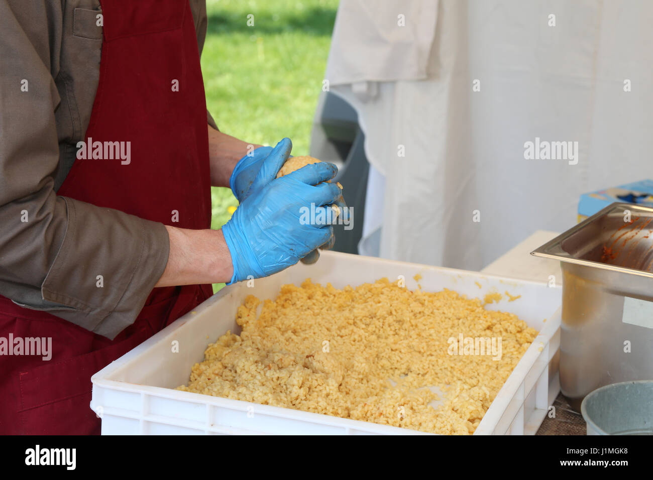experienced cook with blue gloves on a street food stall creates rice ...