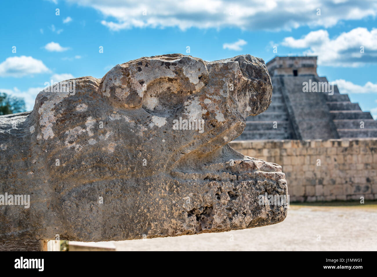 Stone snake head in Chichen Itza, Mexico with the Pyramid of Kukulcan ...