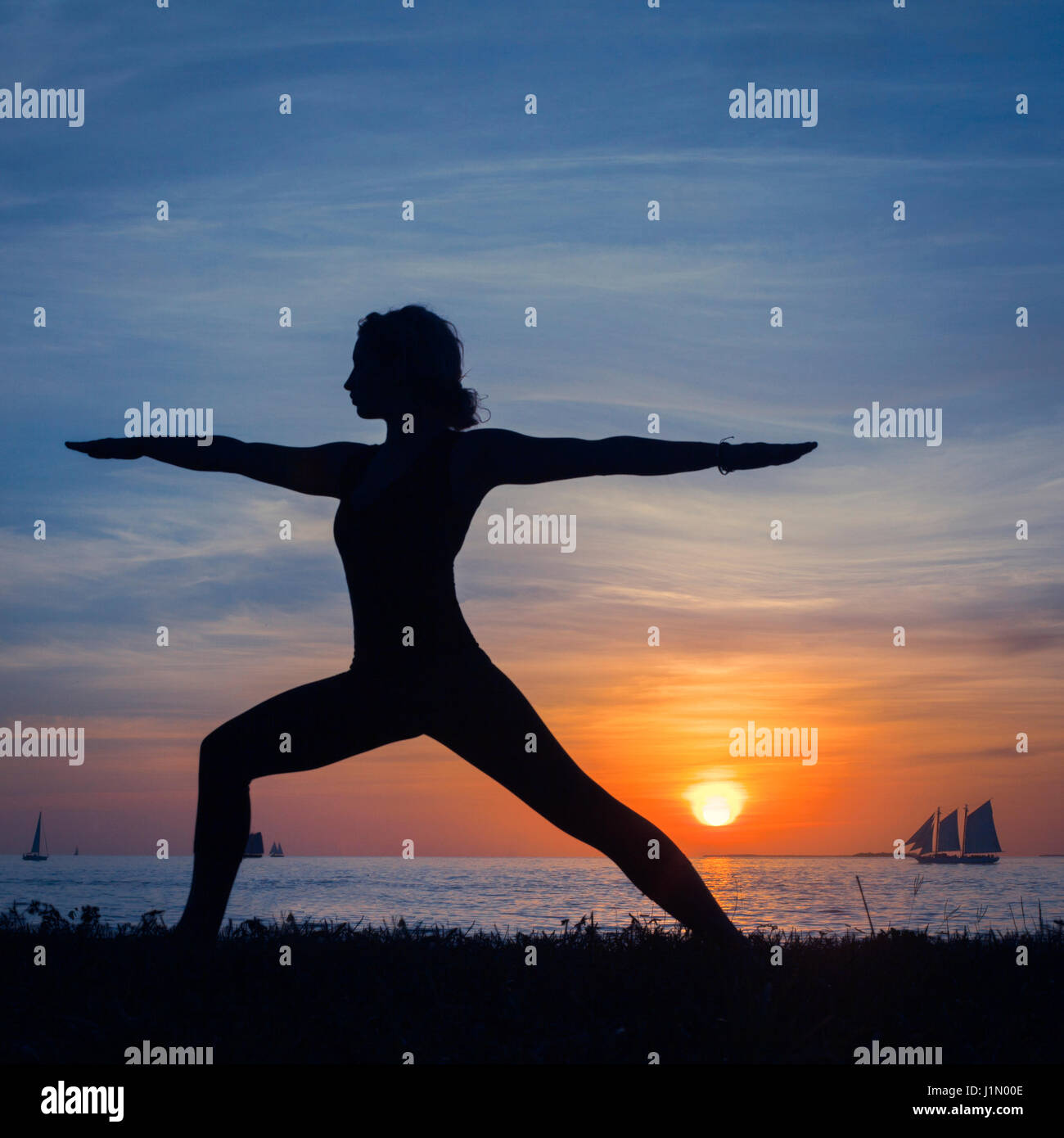 Woman doing yoga with the sunset and ocean behind her. Girl is in a ...